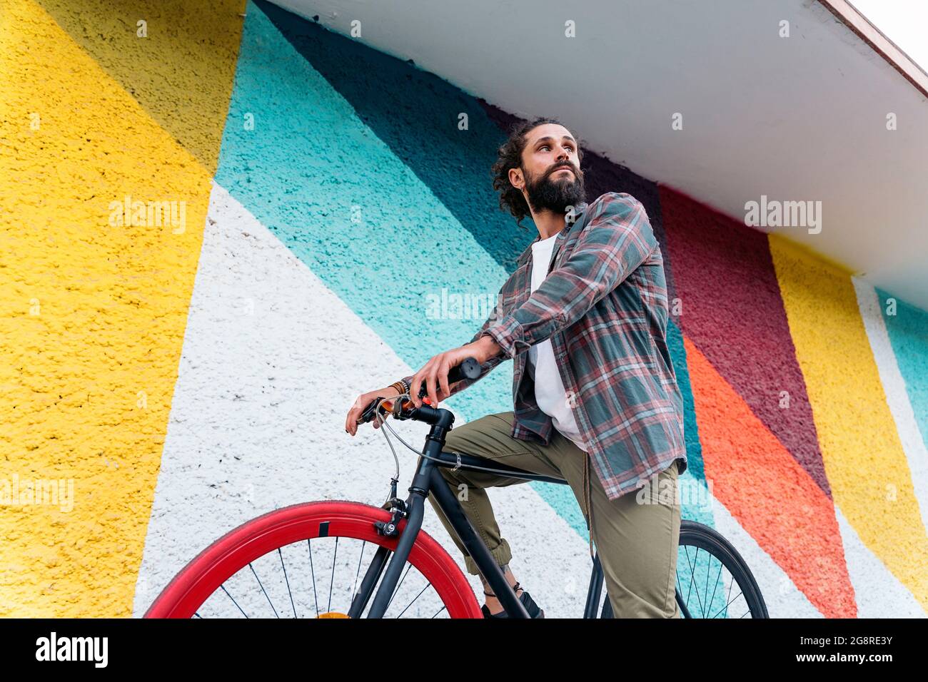 Cool man with big beard riding his bike against colorful background and ...