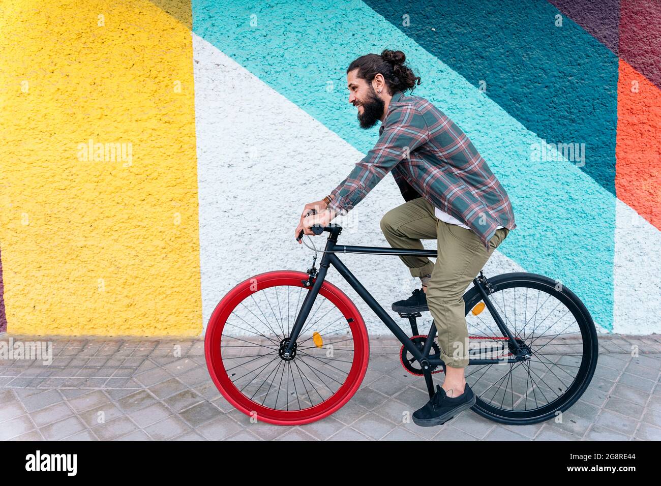 Cool man with big beard riding his bike against colorful background and ...