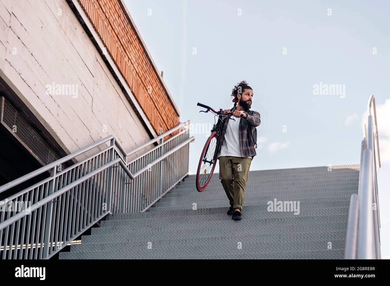 Cool hipster man carrying his bike while walking down stairs in the ...
