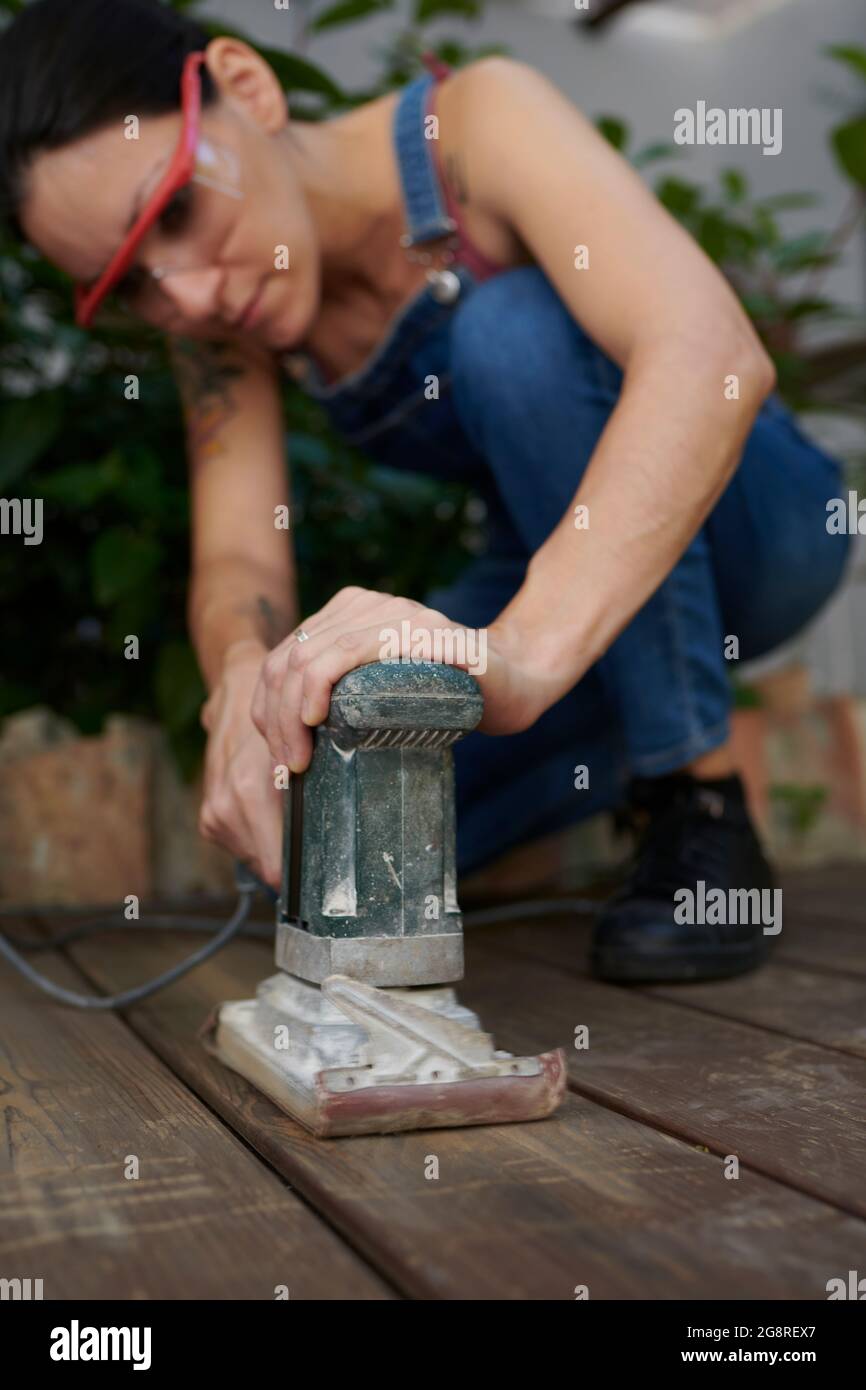 A young woman sanding wood with an electric sander Stock Photo - Alamy