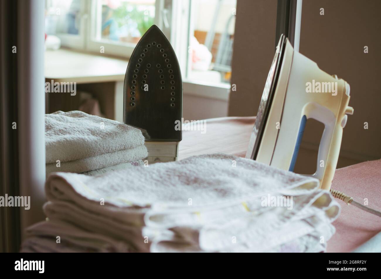 An iron and a Stack of ironed linen on ironing board Stock Photo - Alamy