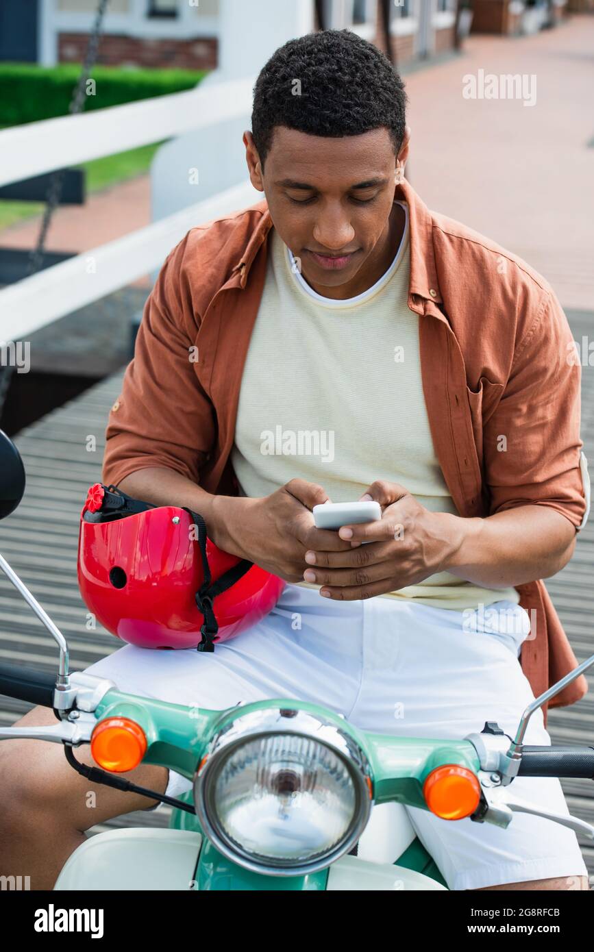 young african american man on scooter messaging on mobile phone Stock ...