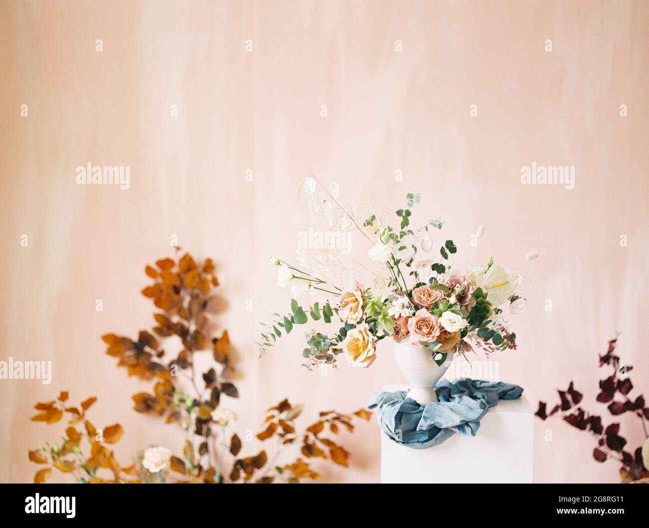 asymmetrical floral arrangement on stand in front of pink background ...