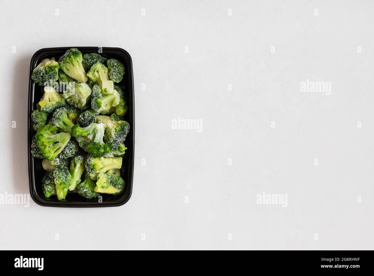Frozen broccoli. Frozen vegetables in a plastic container on a white ...