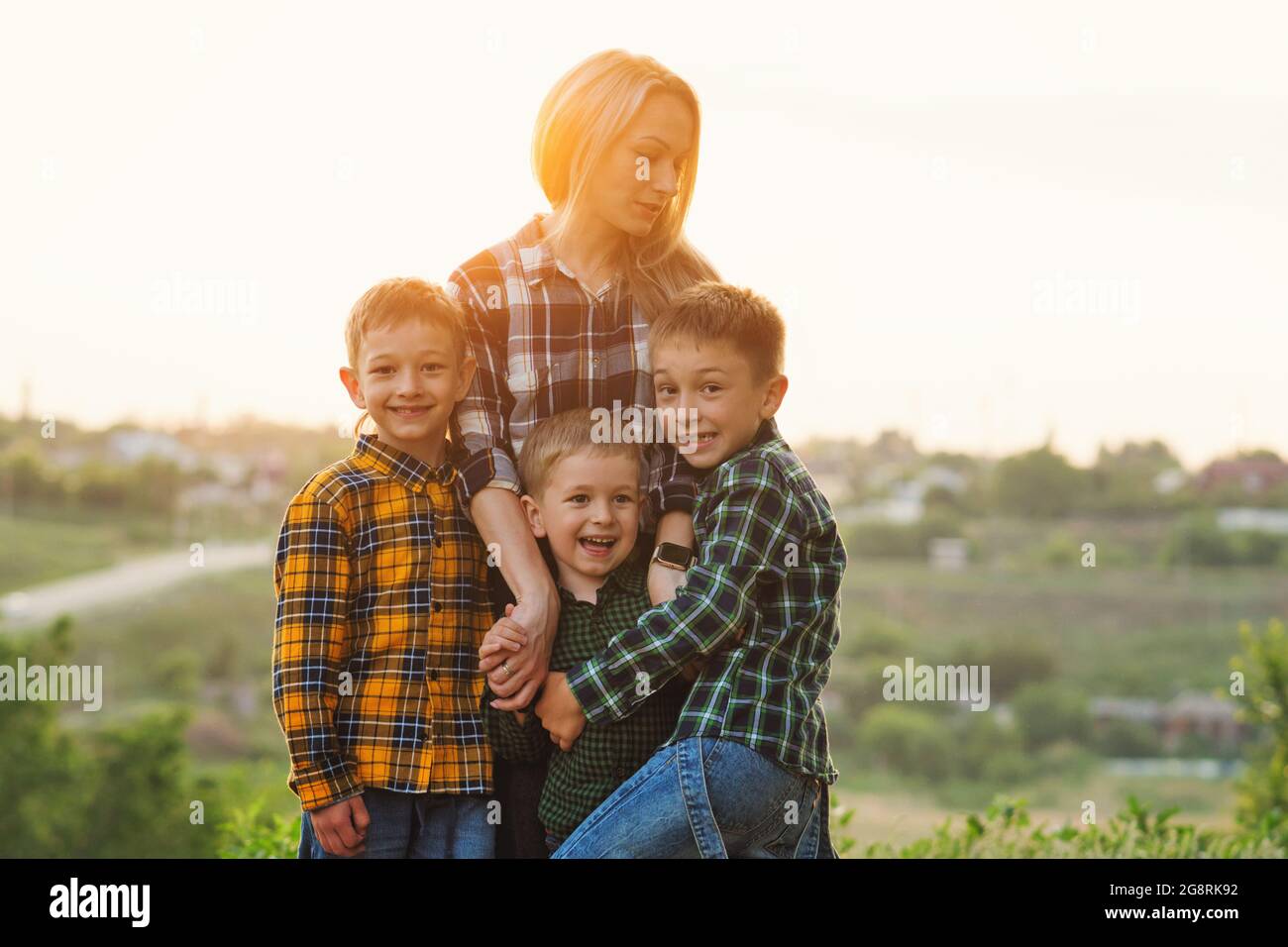 Young mother and her three son are playing at sunset time. Friendly ...