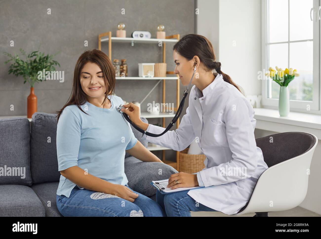 Female doctor listens to the heart and breath of a young woman through ...