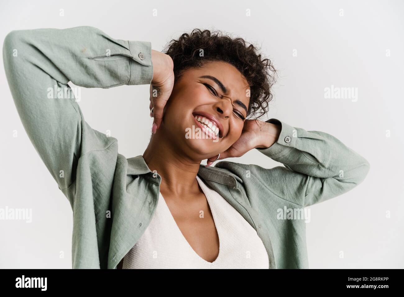 Young black woman in shirt laughing and covering her ears isolated over ...