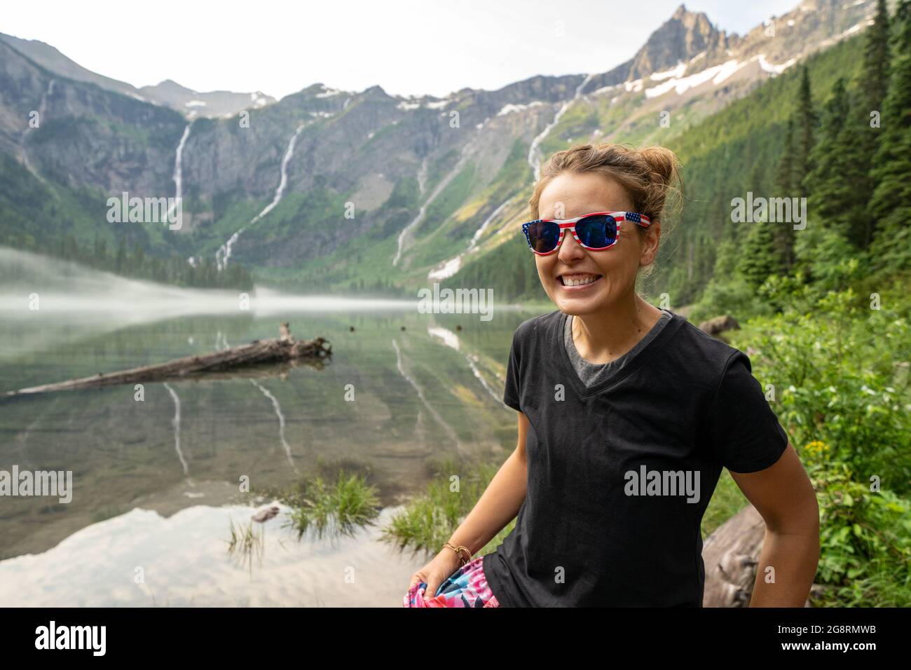 Adult woman hiker smiles and poses at Avalanche Lake in Glacier ...