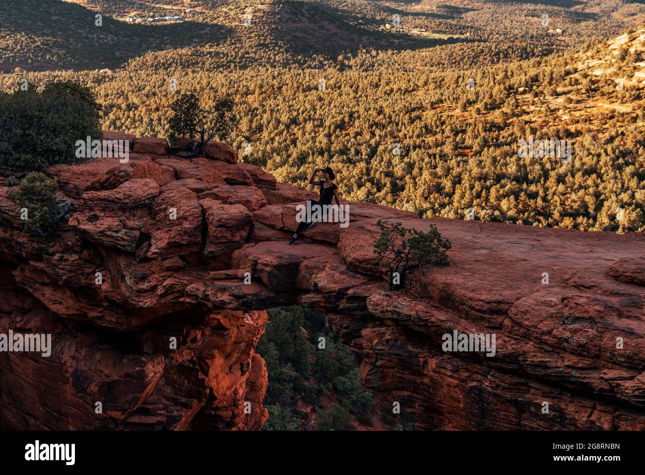 Tourist sitting on a natural land bridge at Coconino National Forest in ...