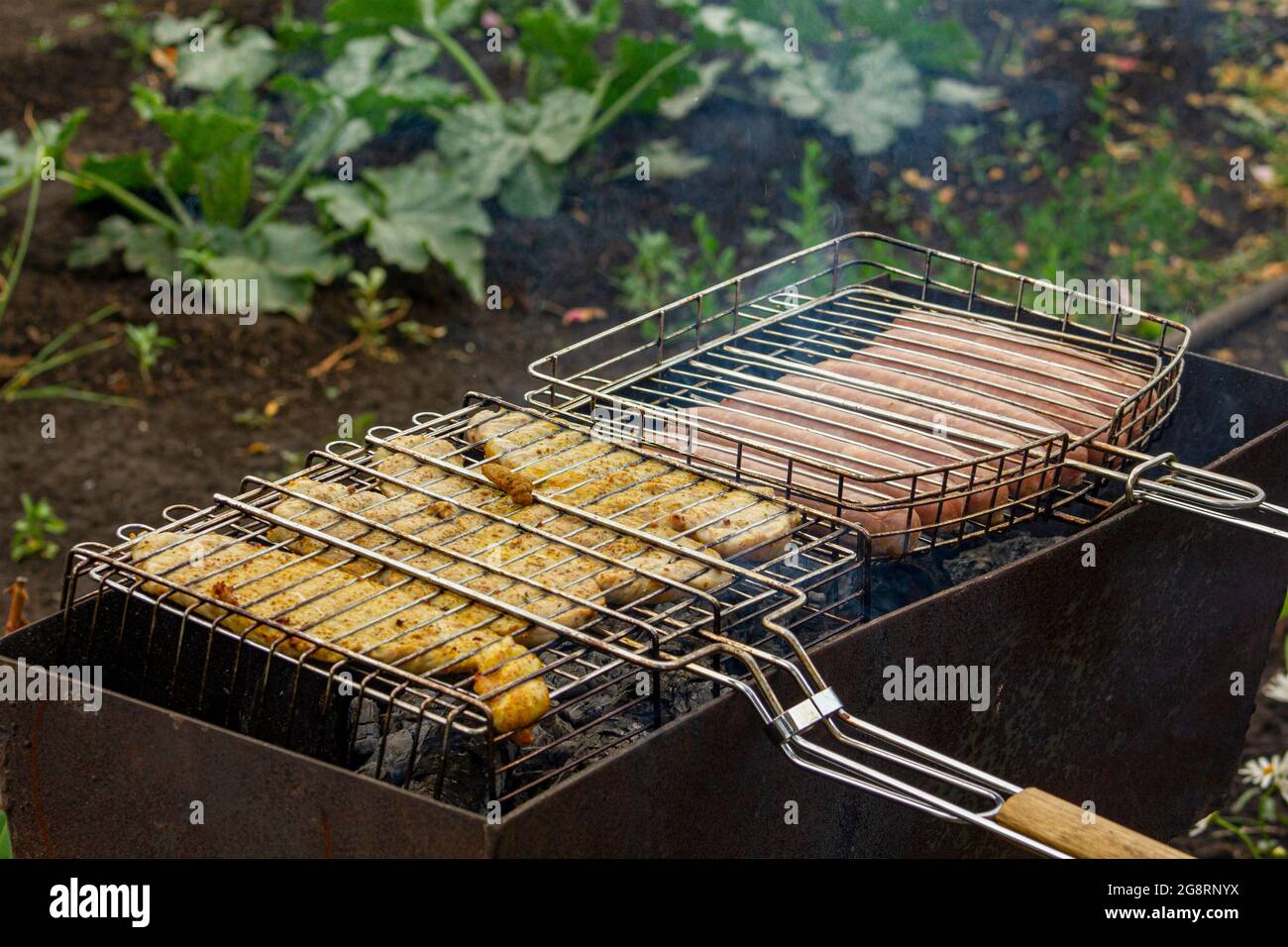 Two grills with meat sausages and chicken chop on a charcoal grill ...