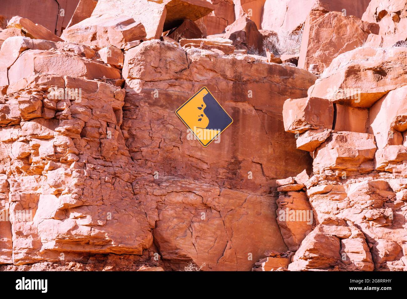 A beware of falling rocks sign posted to a cliff of red rocks in Utah ...