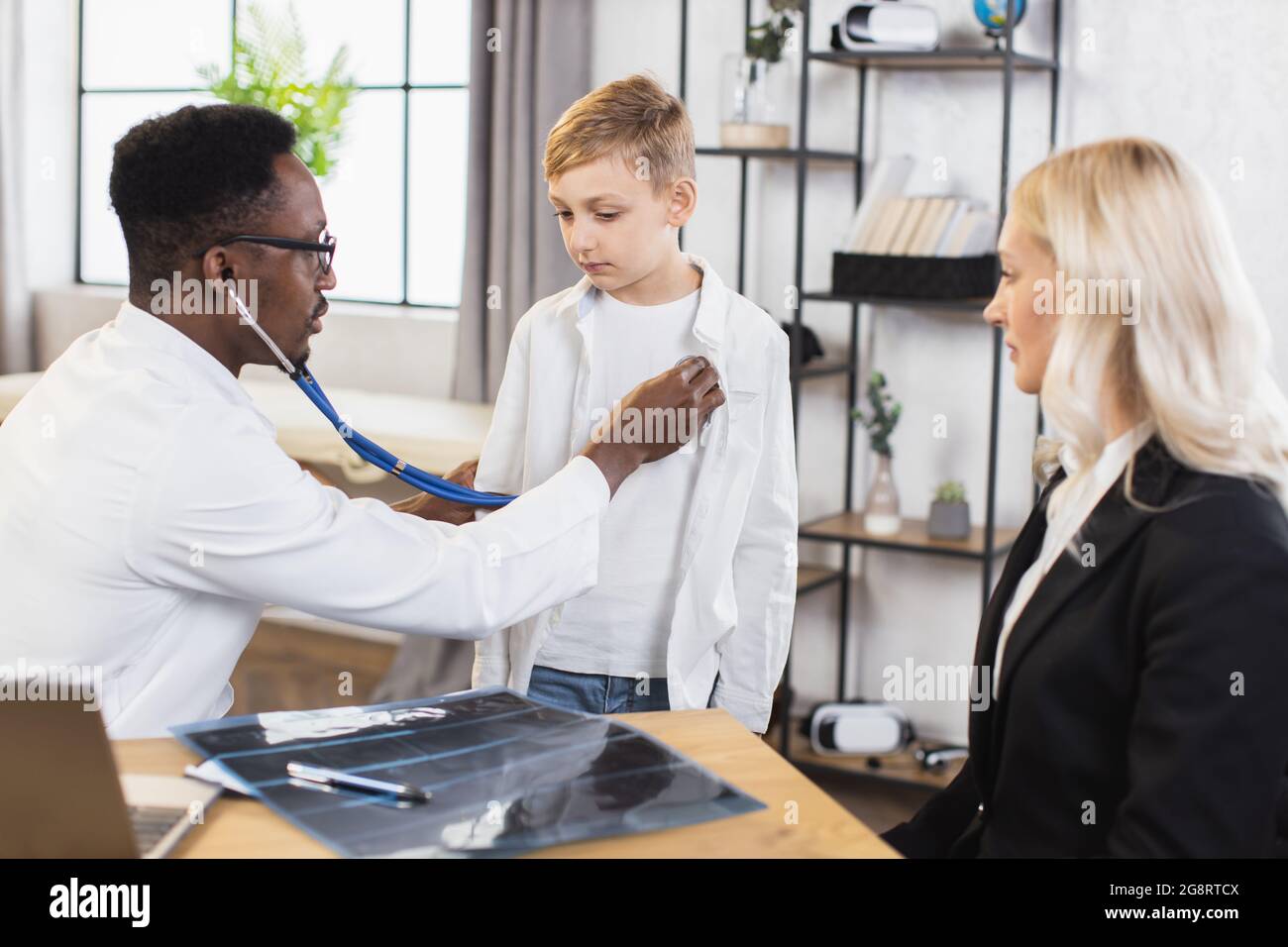 Experienced black pediatrician using stethoscope for examining ...