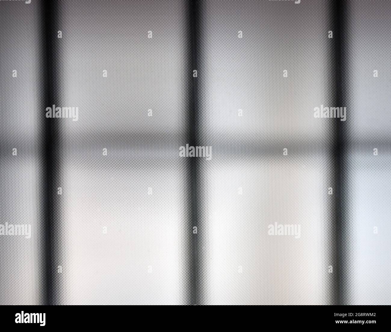 detail of a translucent textured glass in a window and a grille behind ...