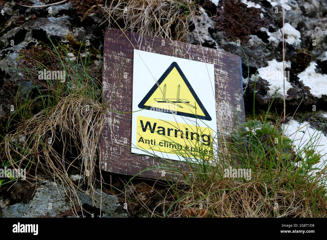 Anti climbing spikes warning sign on an old stone castle wall Stock ...