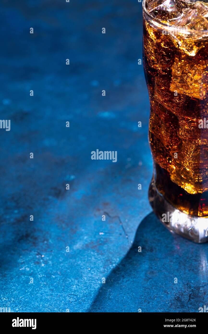 Cold cola with lemon and ice on blue background Stock Photo - Alamy