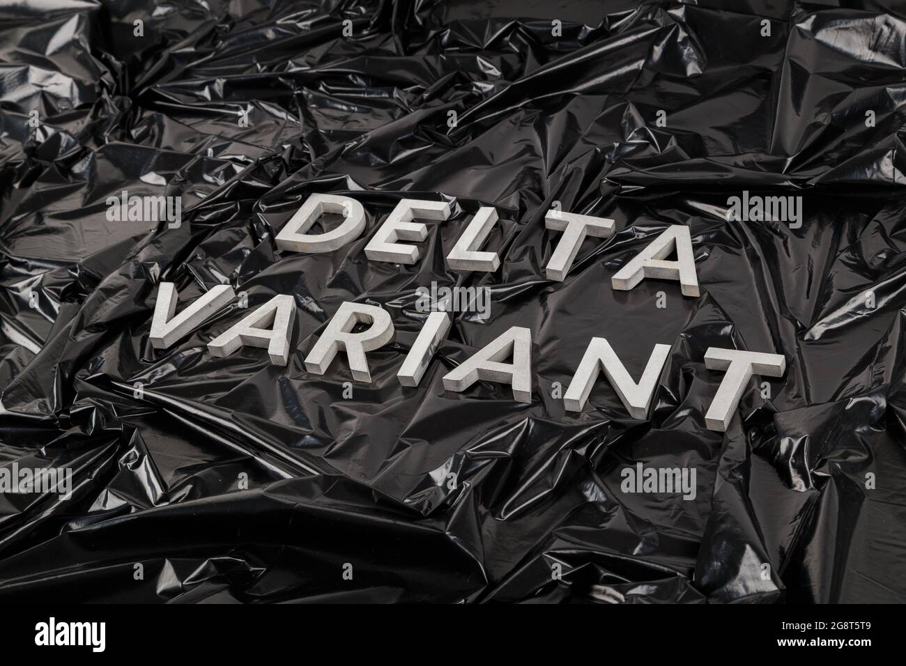 words delta variant laid with silver metal letters on crumpled black ...