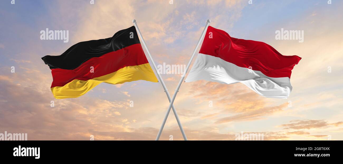 flags of Germany and Monaco waving in the wind on flagpoles against sky ...