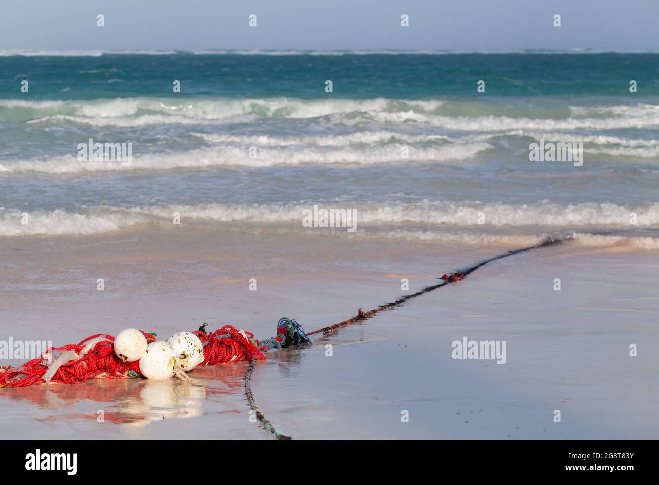 Red white floats on a rope lay over wet sandy coast of Bavaro beach ...