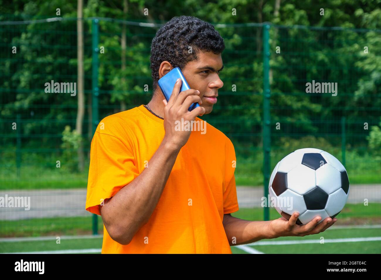 Brazilian man holding soccer ball and use smartphone on sports court ...