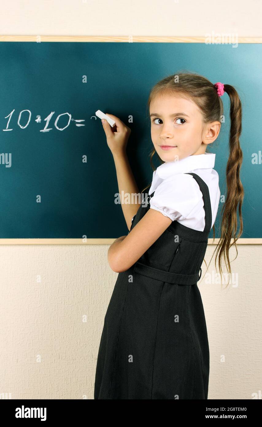beautiful little girl writing on classroom board Stock Photo - Alamy