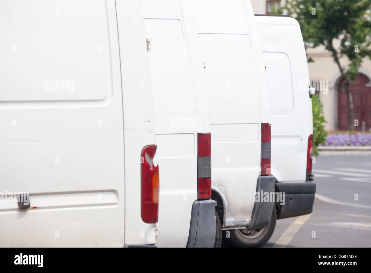 Picture of white delivery trucks, vans, parked in row, waiting for ...