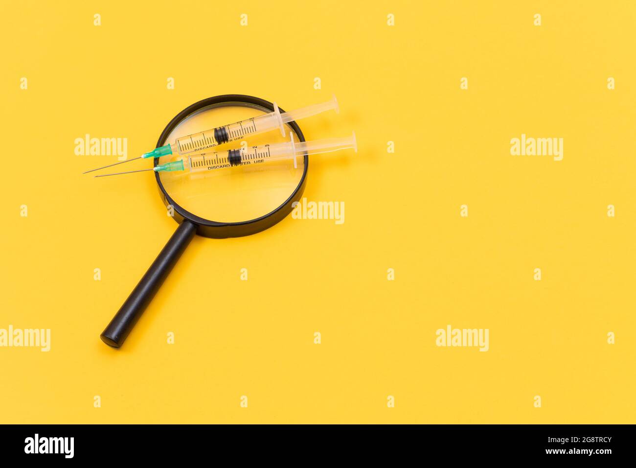 A Magnifier with Medical Syringe Lying on Yellow Table - Vaccination ...