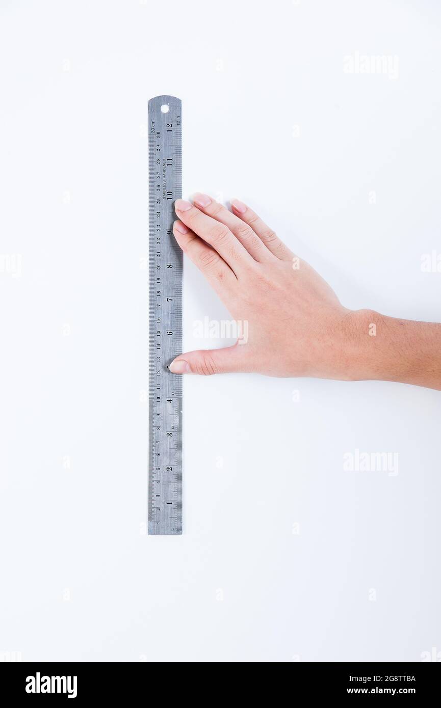a man's hand holding stainless steel ruler to measure something Stock ...