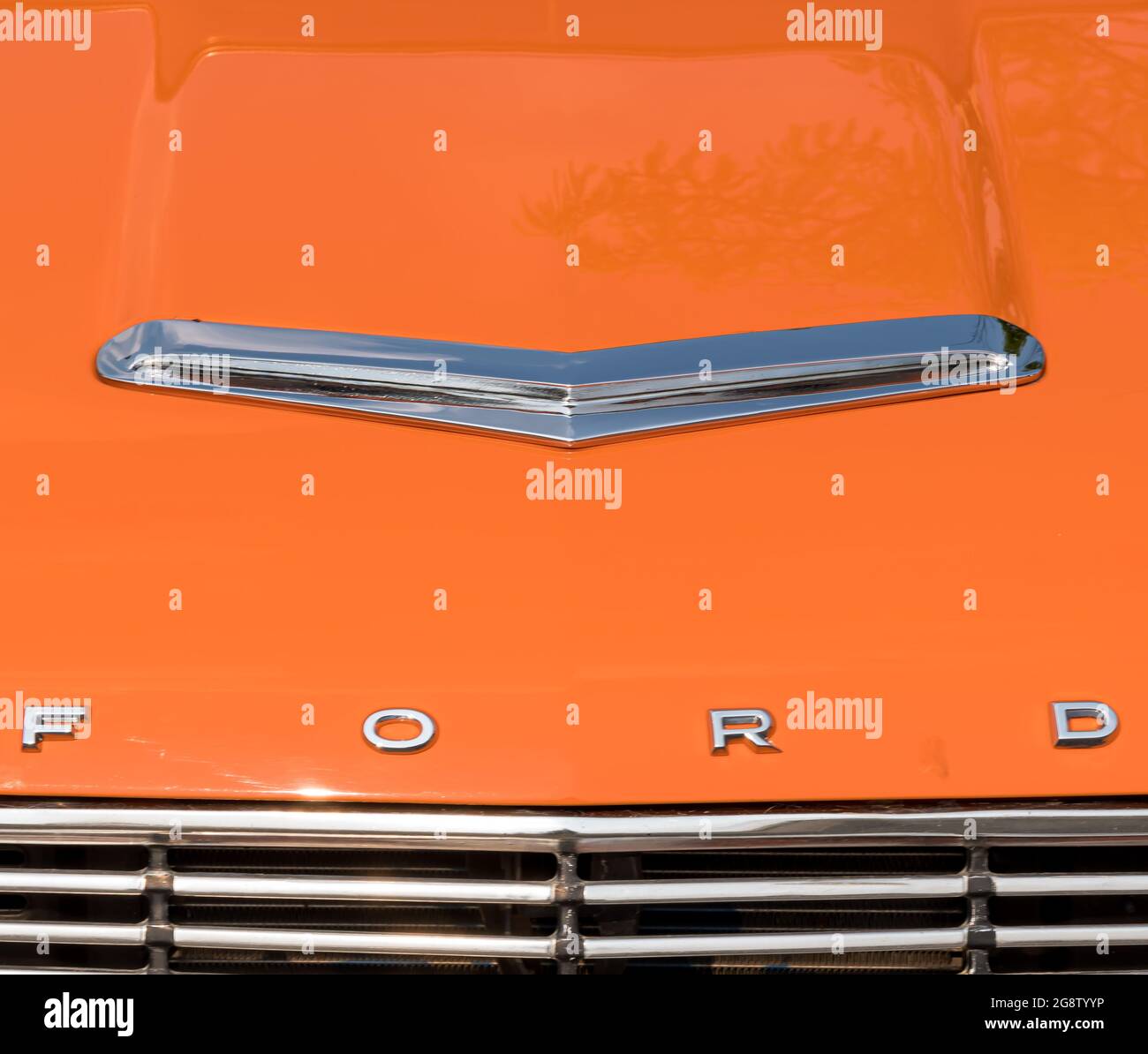 An orange hood of a vintage Ford automobile with a metal hood scoop ...