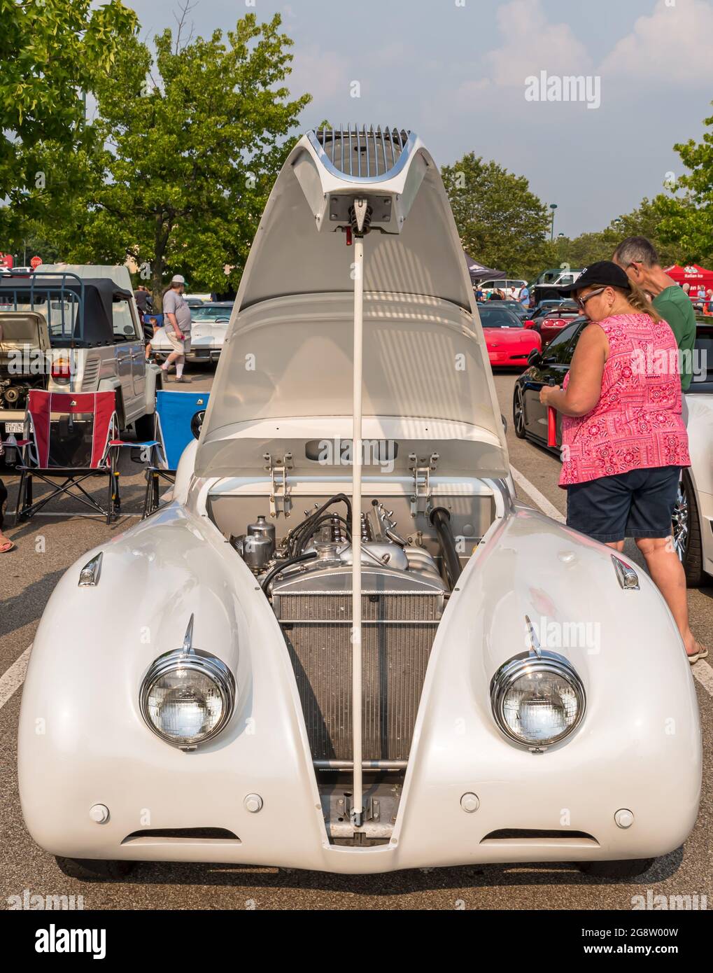 A vintage white Jaguar with it's hood open at a summer car show in ...