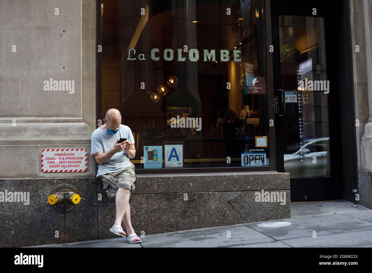 A man leans against window glass of La Colombe coffee shop on Wall St ...