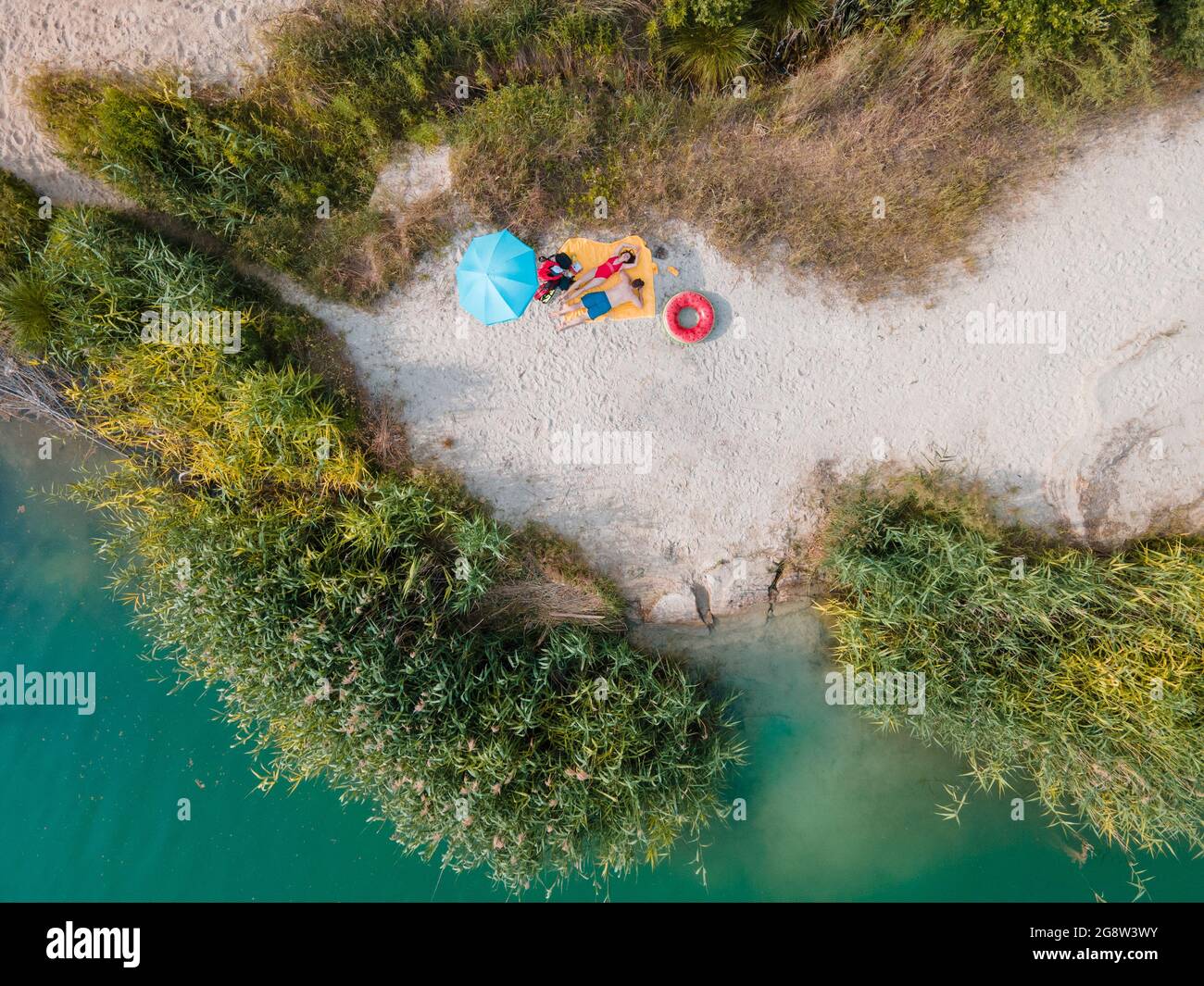 couple laying on blanket sunbathing at sandy beach blue azure water ...