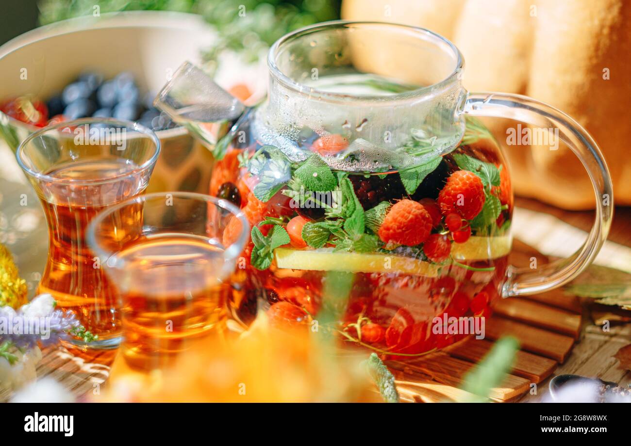 natural aromatic fruit tea in a transparent teapot and in a cup among ...