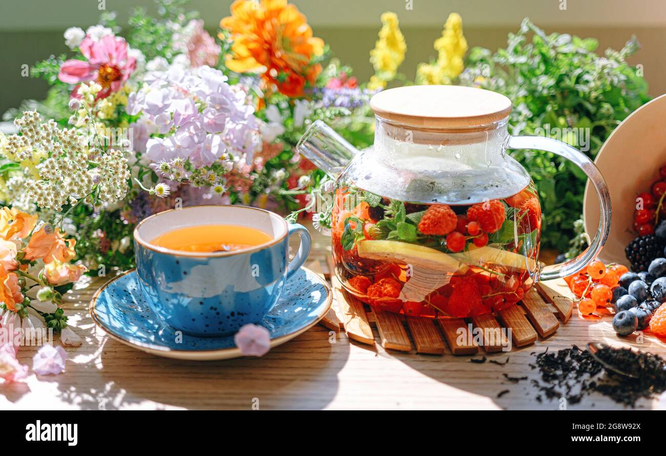 natural aromatic fruit tea in a transparent teapot and in a cup among ...
