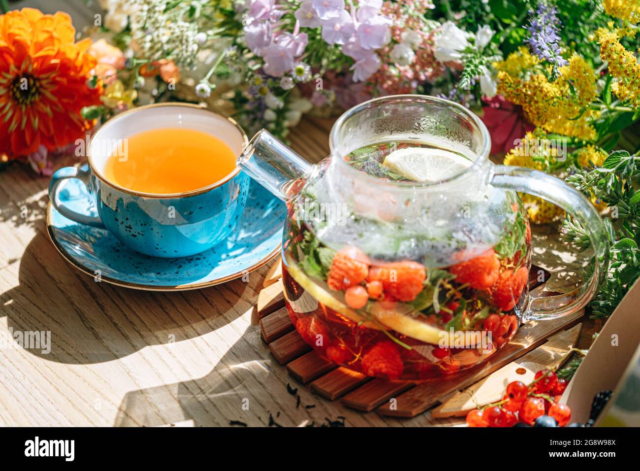 natural aromatic fruit tea in a transparent teapot and in a cup among ...