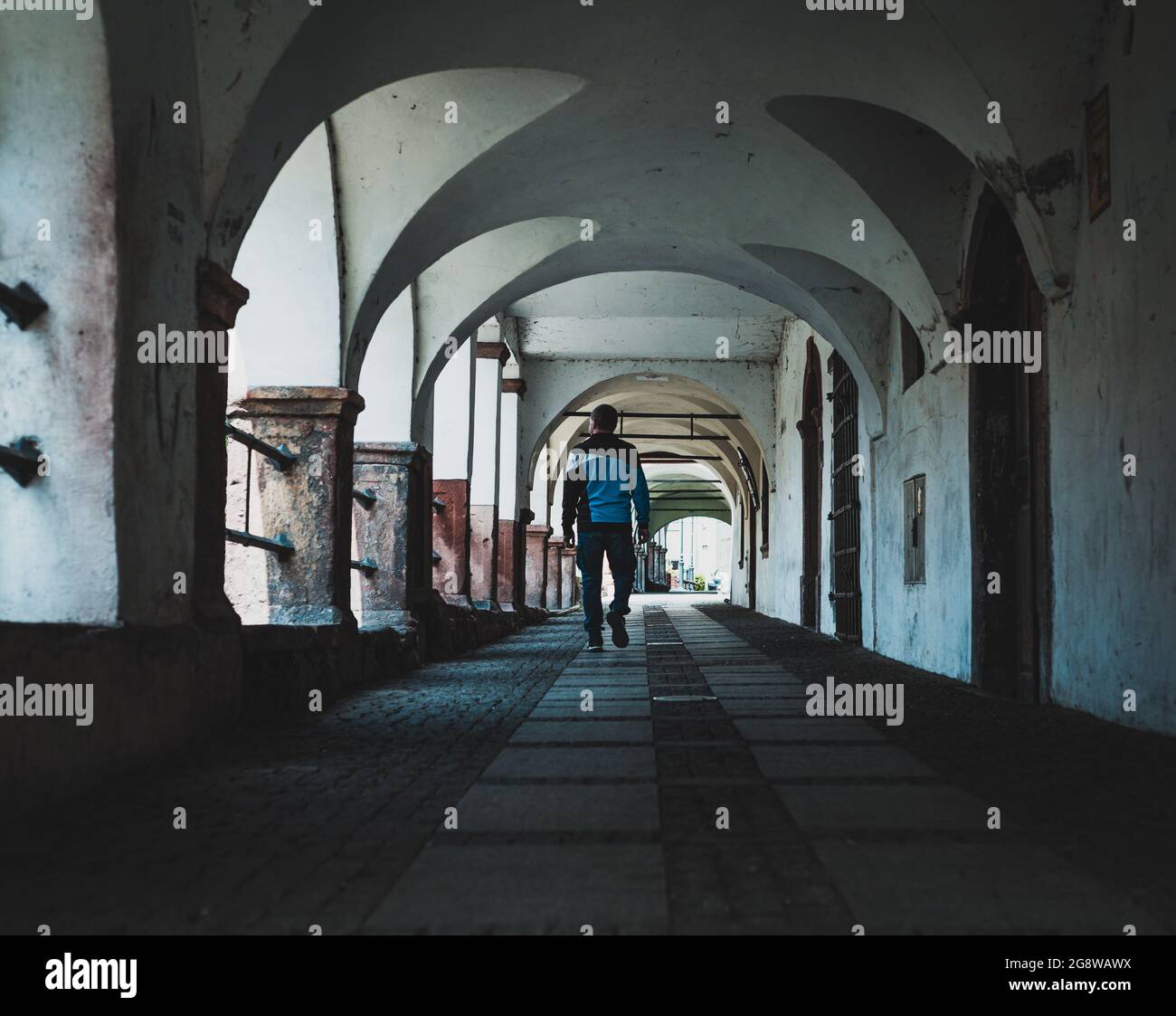 arcade passageway in small town, walking man seen from behind Stock ...