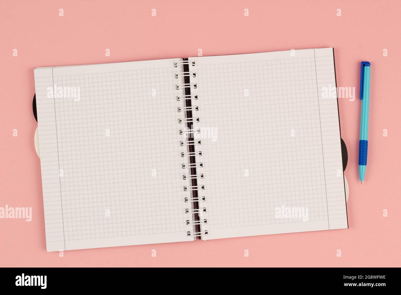 Open school squared notebook and pen on the pink background. Blank ...