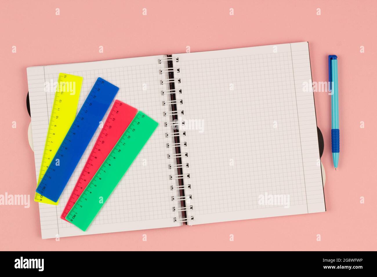 Open school squared notebook, pen and color rulers on the pink ...