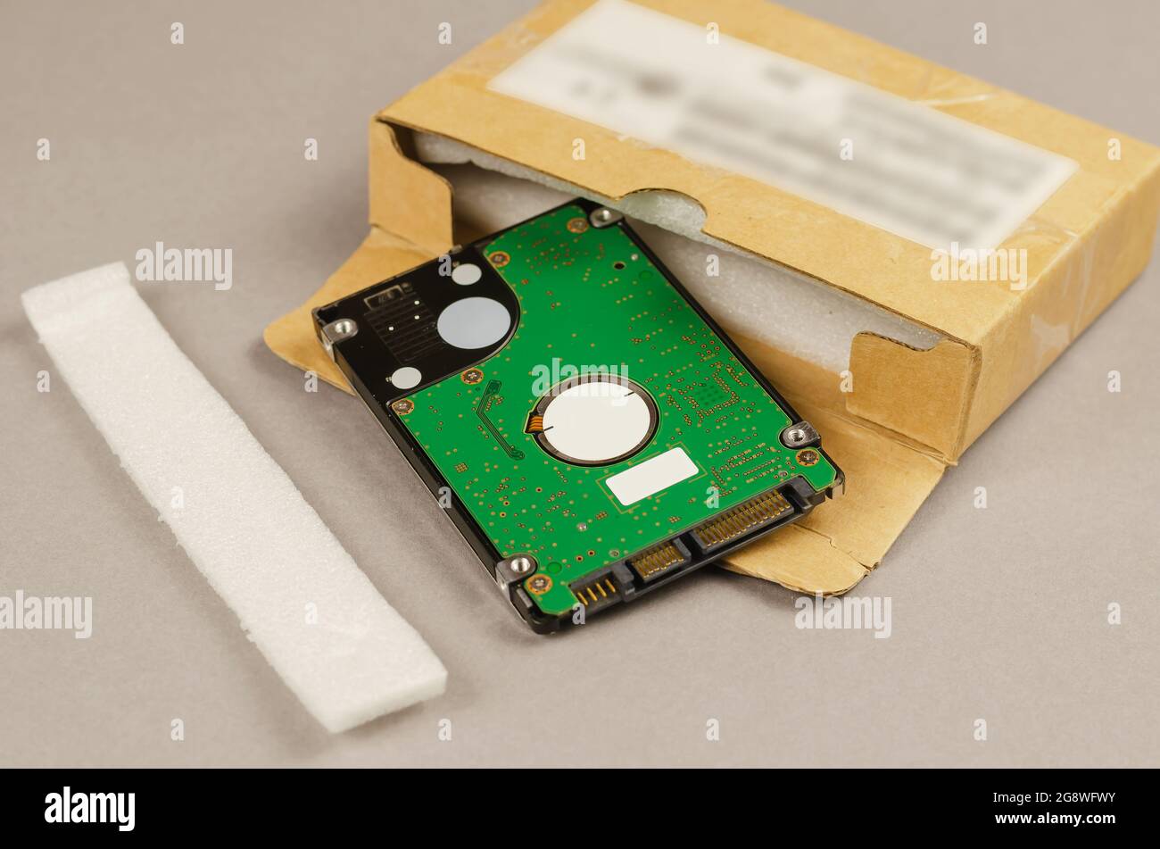 Brown cardboard box and internal computer hard drive on gray background ...