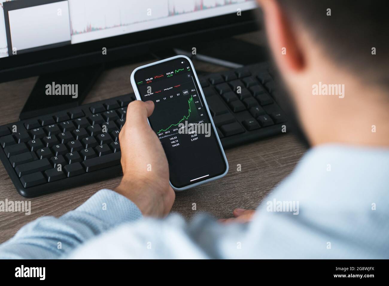Stock market phone in the hand and desktop computer green and red ...