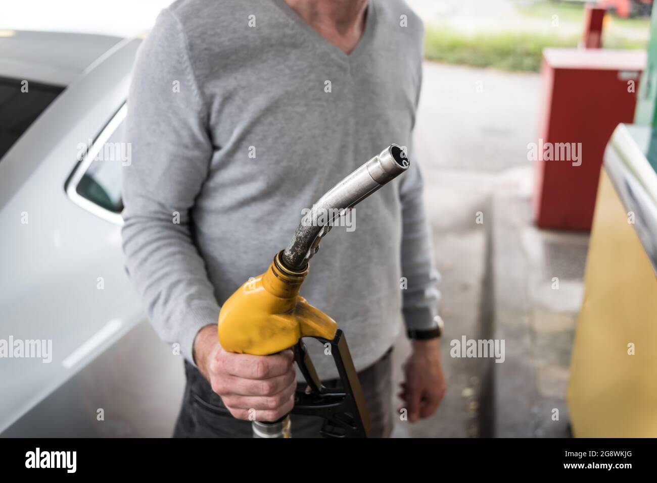 Man holding a yellow fuel pump nozzle Stock Photo - Alamy