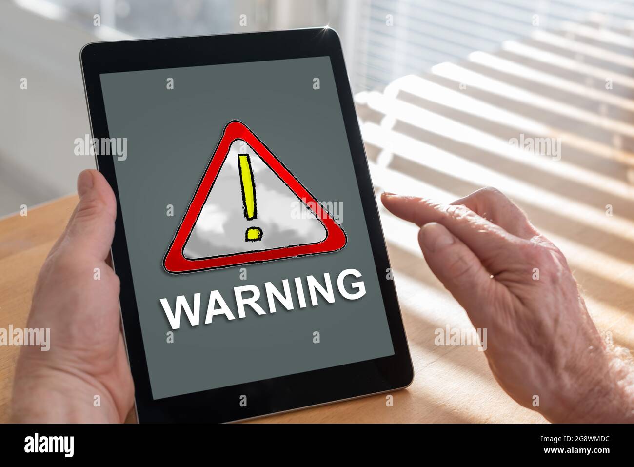Tablet screen displaying a warning concept Stock Photo - Alamy