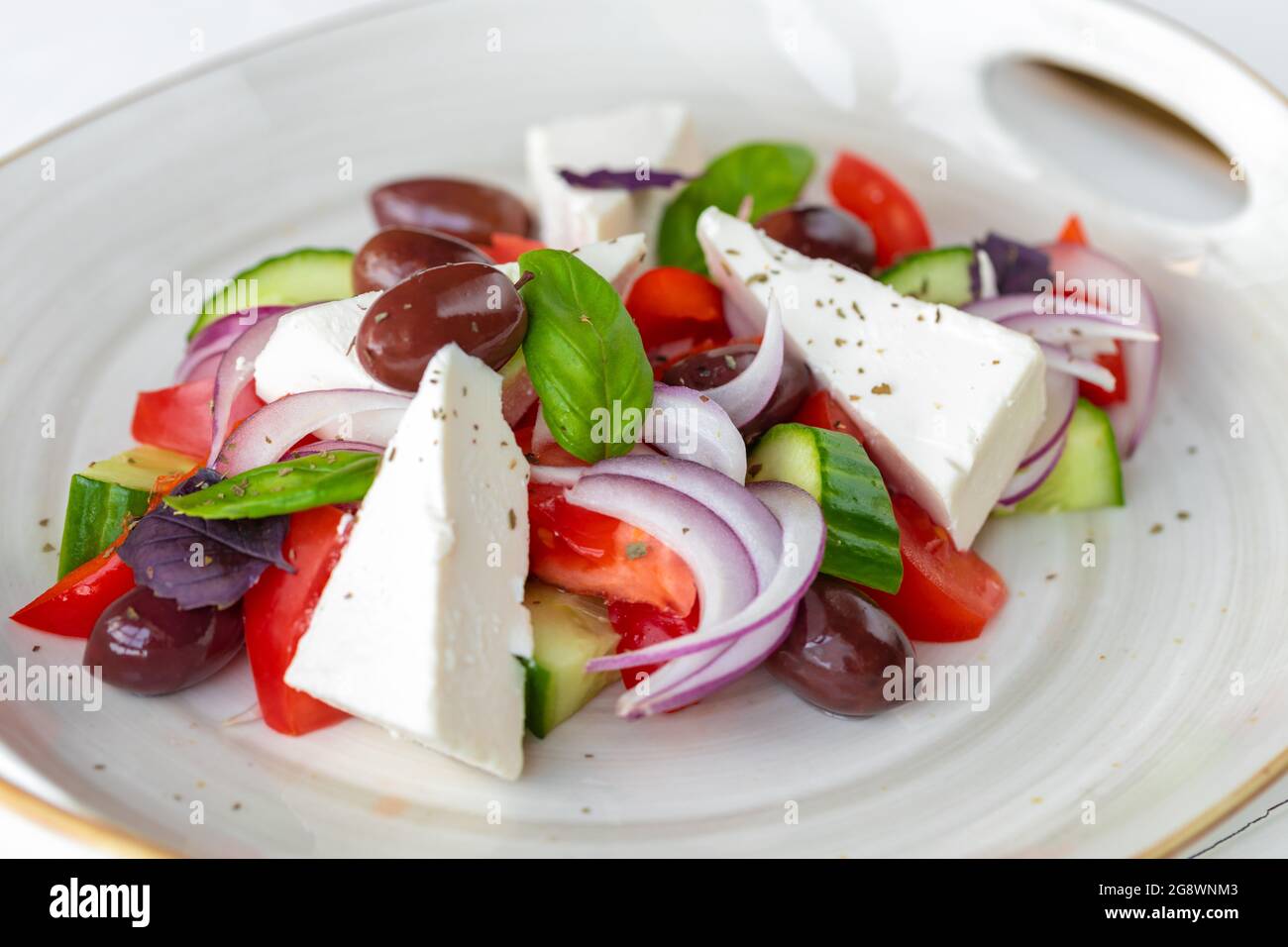 Greek salad in plate on white wooden background Stock Photo - Alamy