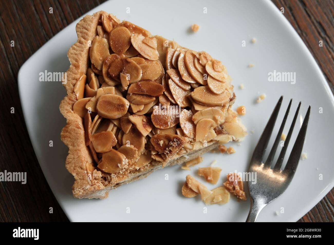 Eating almond pie in the cafe, closeup piece of almond pie on white ...