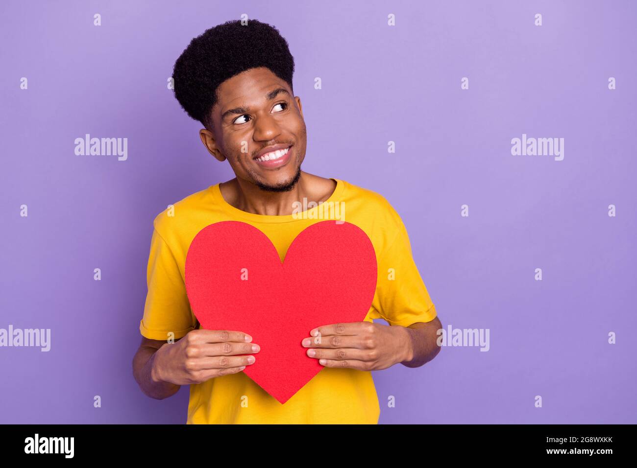 Photo of positive afro american young man look empty space hold red ...