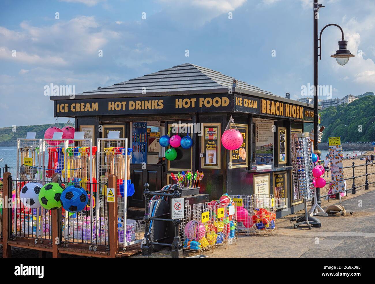 A fast food kiosk near the entrance to a beach with colourful beach ...