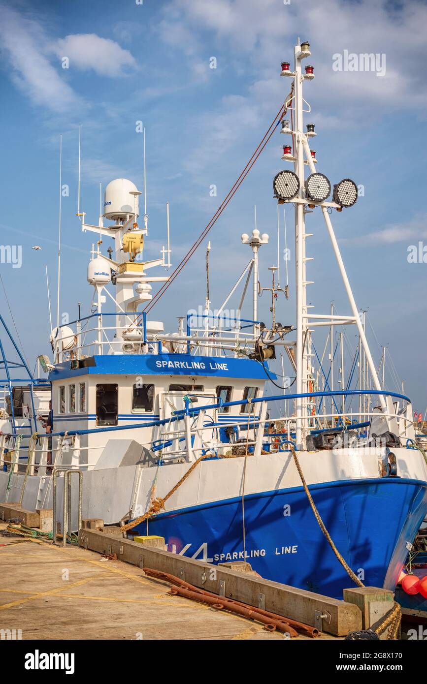 A freshly painted trawler is moored alongside a wharf. Antennae and ...