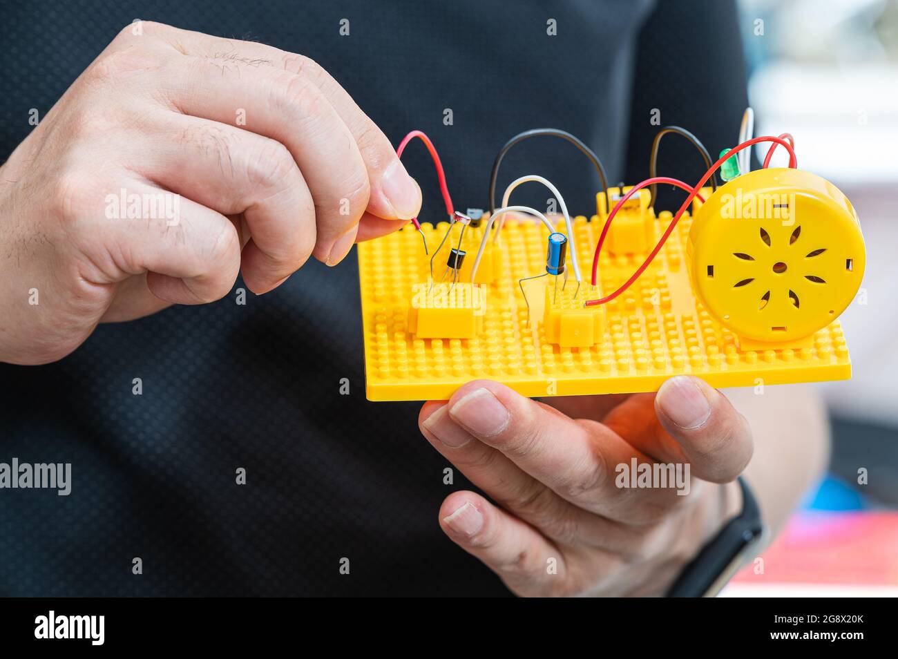Student's hand holding an invention kit and connecting electric wires ...