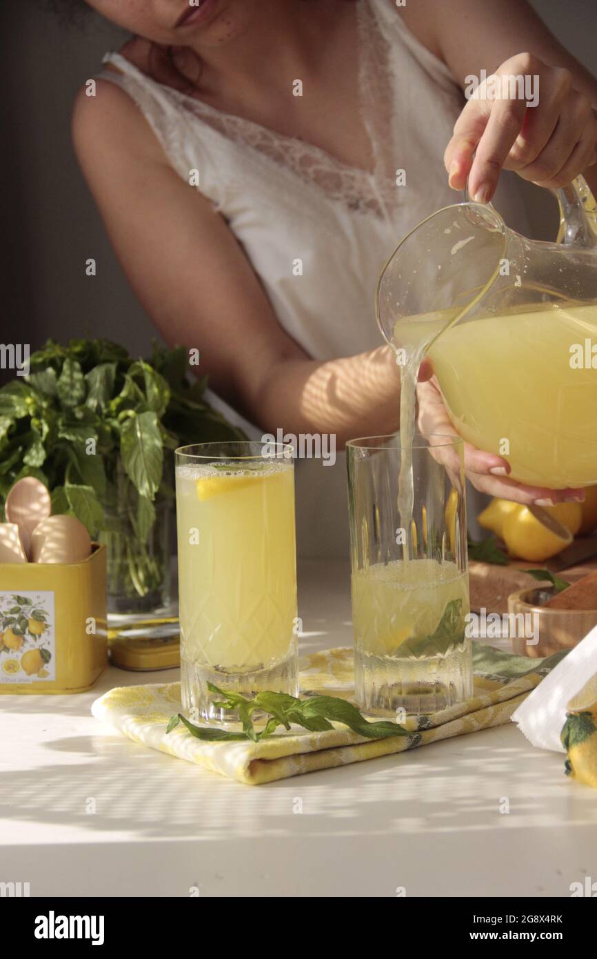 A woman pouring lemonade to a glass on table Stock Photo - Alamy