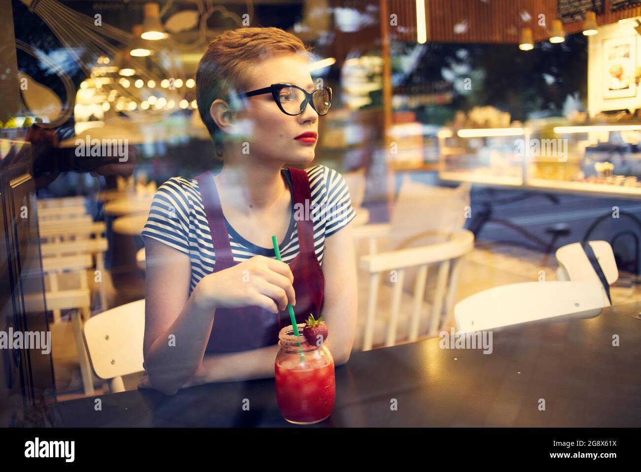 woman with short hair sitting at a table in a cafe cocktail drink ...