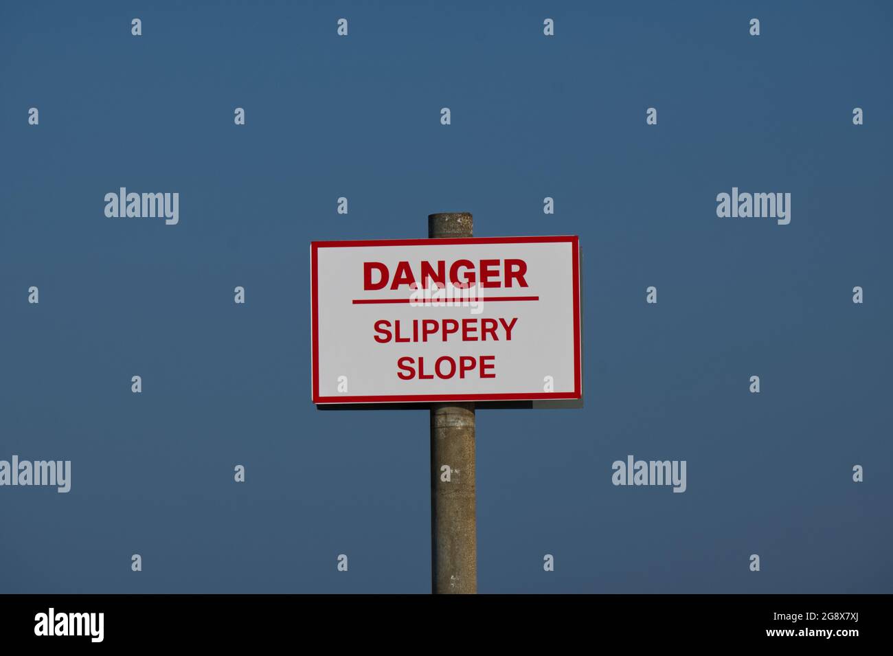 Rectangular red and white danger slippery slope warning sign against hi ...
